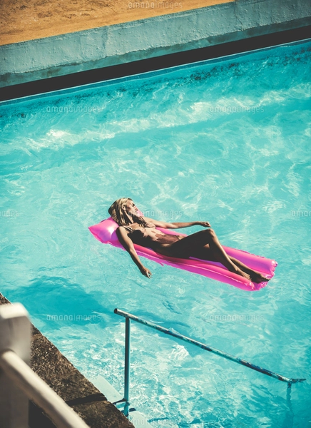 High angle view of a young woman lying on a pool raft in a swimming ...