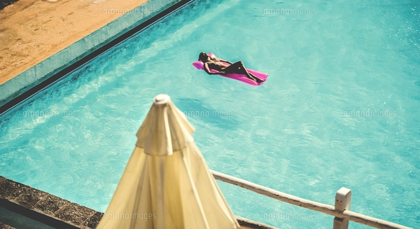 High angle view of a young woman lying on a pool raft in a swimming ...