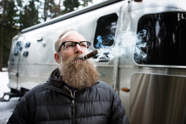 Thoughtful mature man smoking cigar outside caravan in forestの写真素材 ...