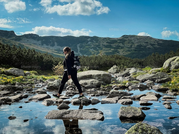 Woman walking on rocks across river in Tatras Mountains in Polandの写真素材 ...