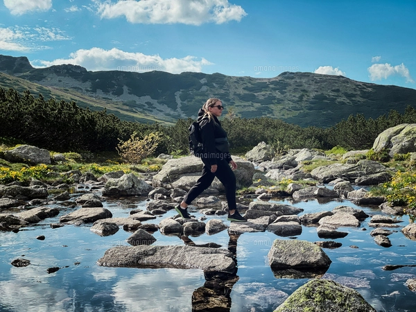 Woman walking on rocks across river in Tatras Mountains in Polandの写真素材 ...